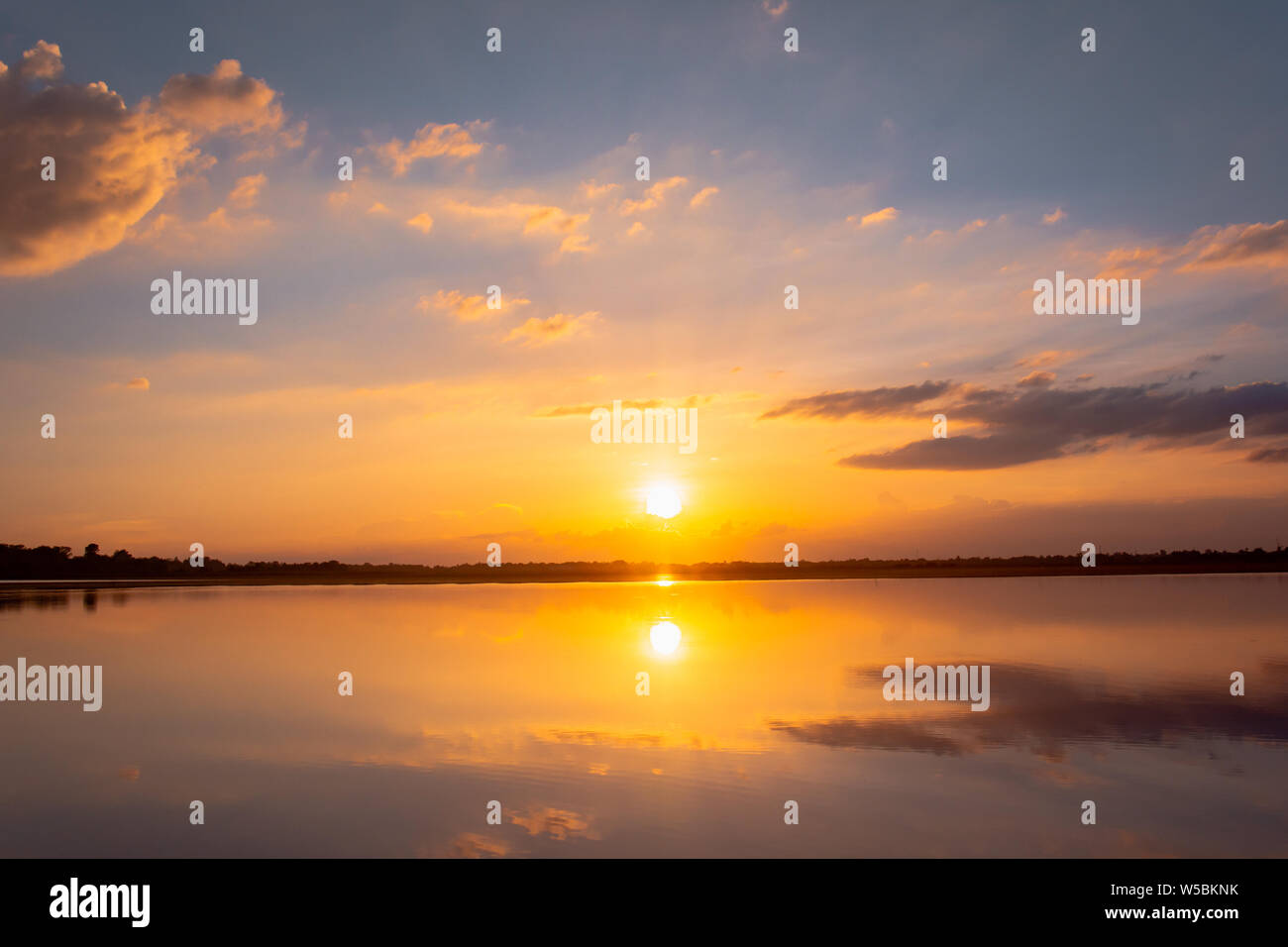 Sunset reflection lagoon. beautiful sunset behind the clouds and blue sky above the over lagoon ...