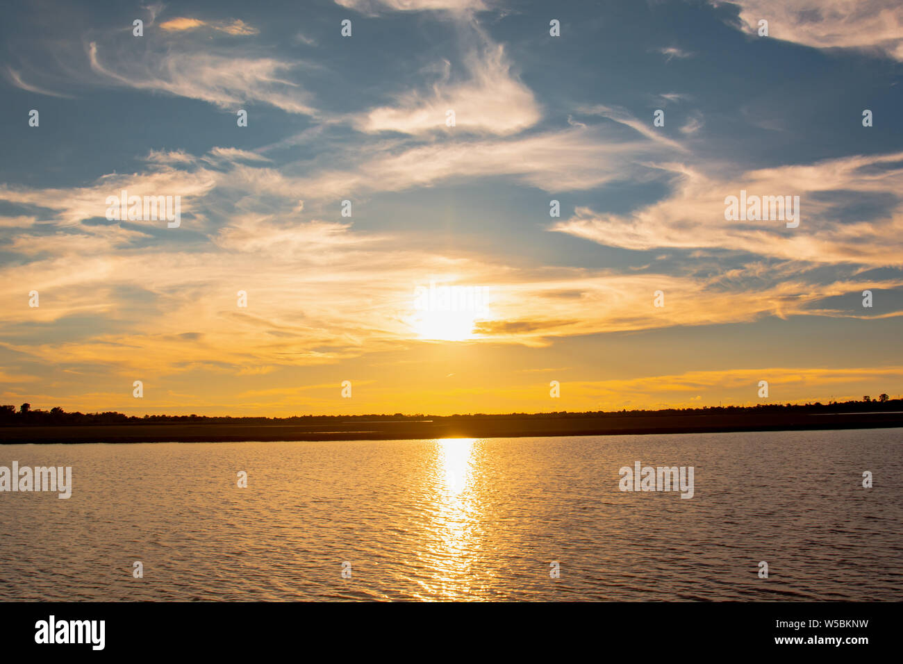 Sunset reflection lagoon. beautiful sunset behind the clouds and blue ...