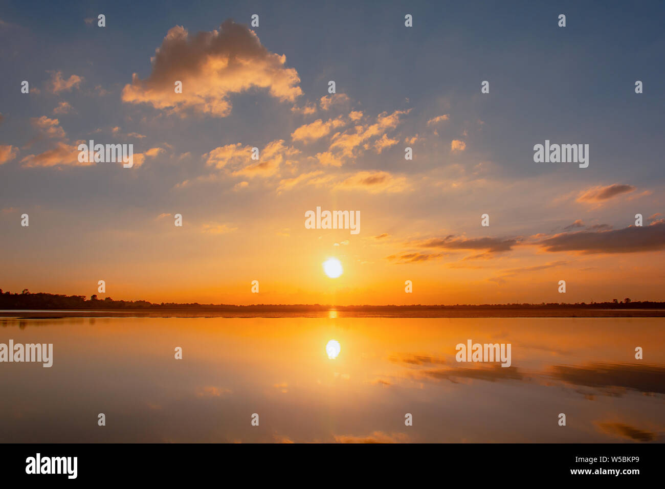 Sunset reflection lagoon. beautiful sunset behind the clouds and blue sky above the over lagoon ...
