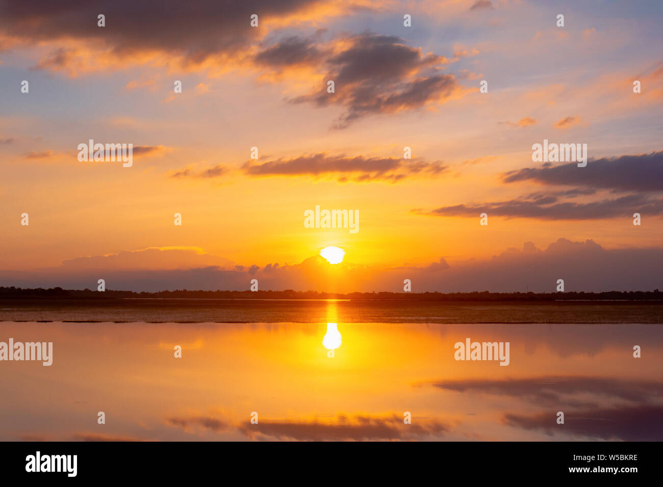 Sunset reflection lagoon. beautiful sunset behind the clouds and blue ...