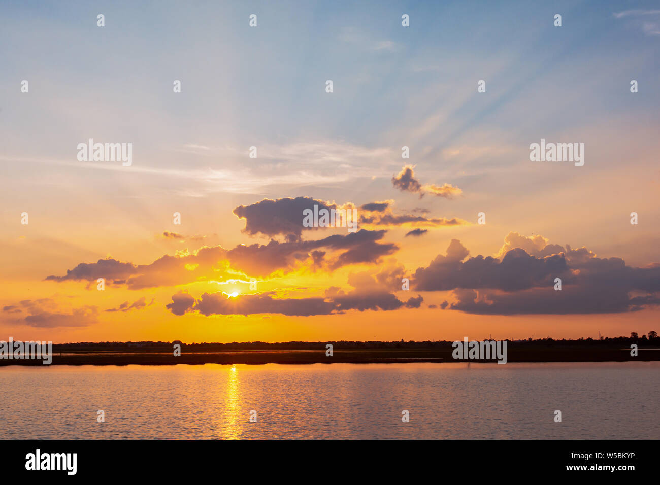 Sunset reflection lagoon. beautiful sunset behind the clouds and blue sky above the over lagoon ...