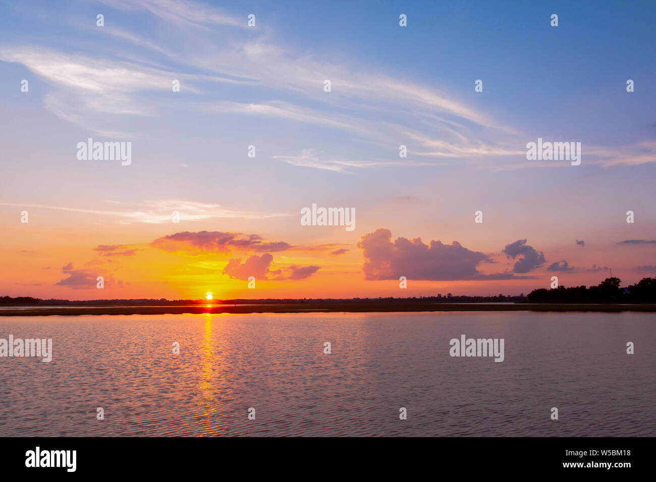Sunset reflection lagoon. beautiful sunset behind the clouds and blue ...