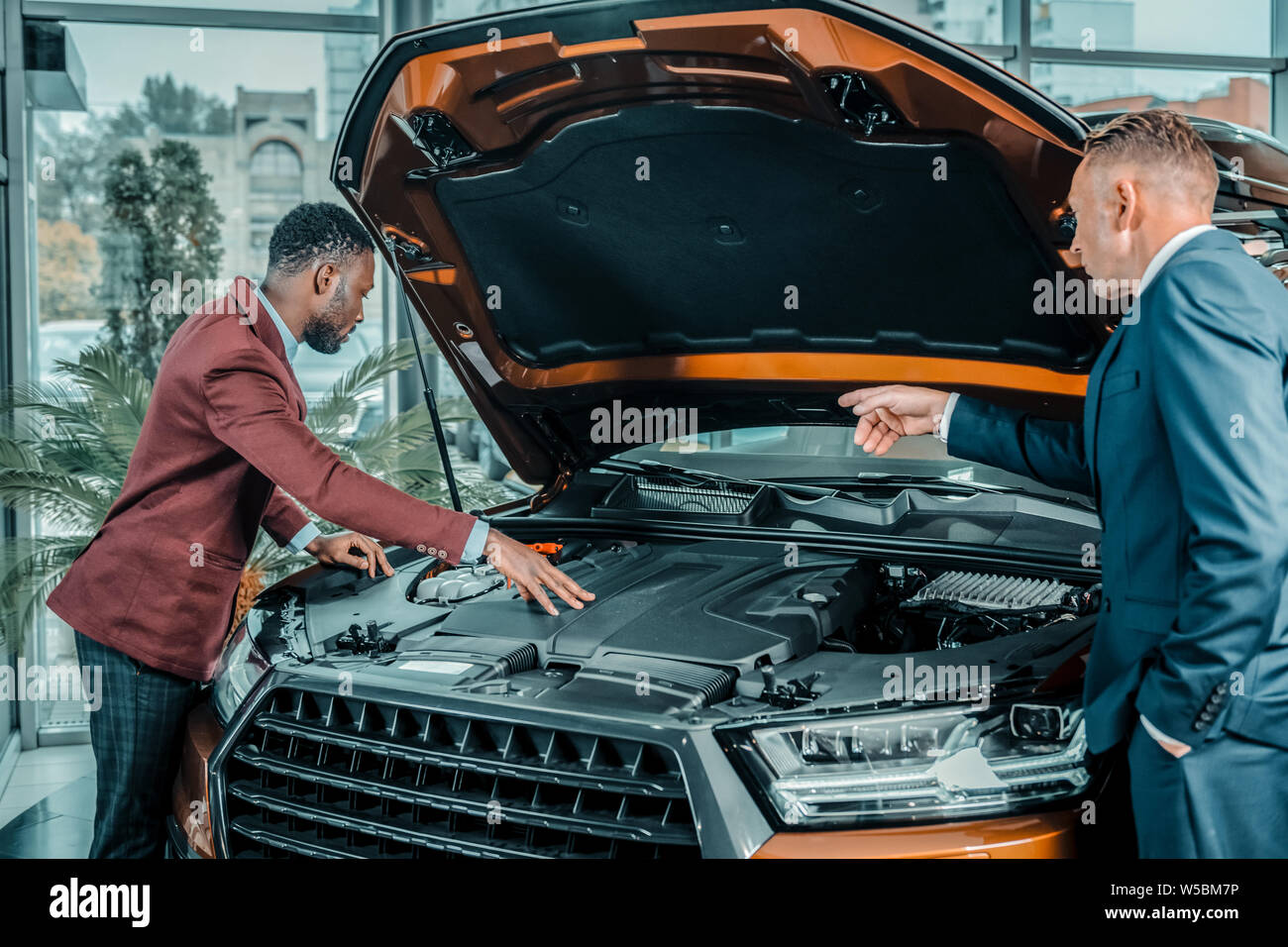 Consultant of car showroom showing the car under capote Stock Photo - Alamy