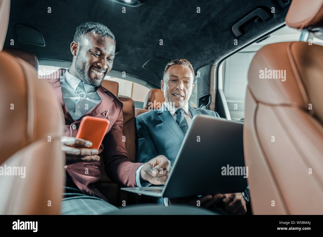 Two smiling men looking at the laptop screen Stock Photo - Alamy
