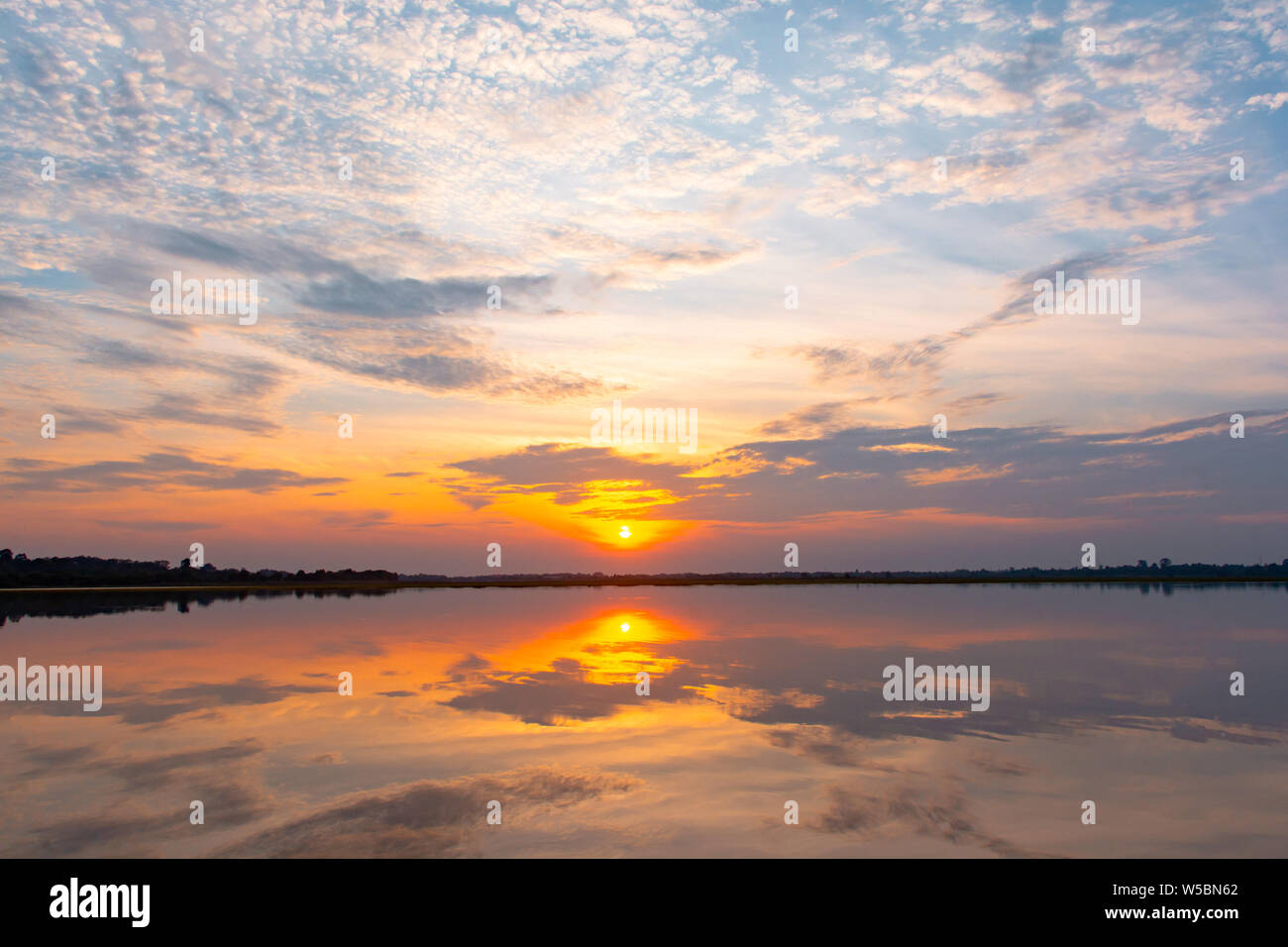 Sunset reflection lagoon. beautiful sunset behind the clouds and blue ...