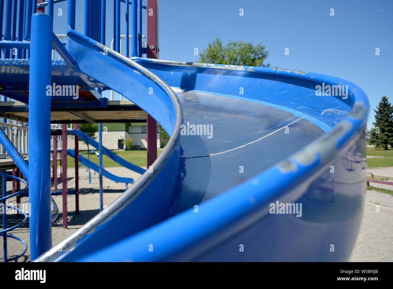 Colourful playground slide in school yard with school in background ...