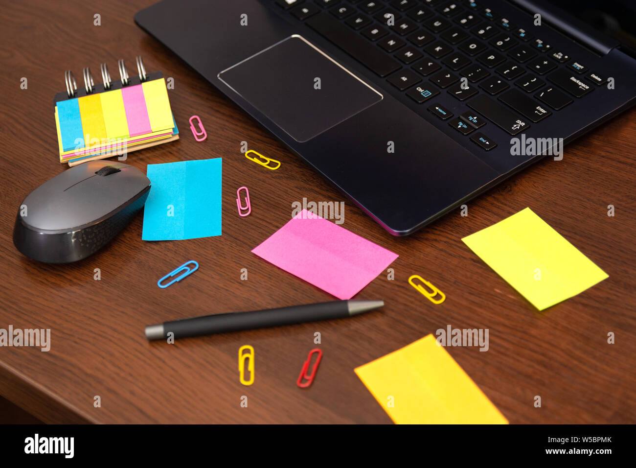 Colorful sticky notes and spilled paper clips, pen, computer mouse and ...