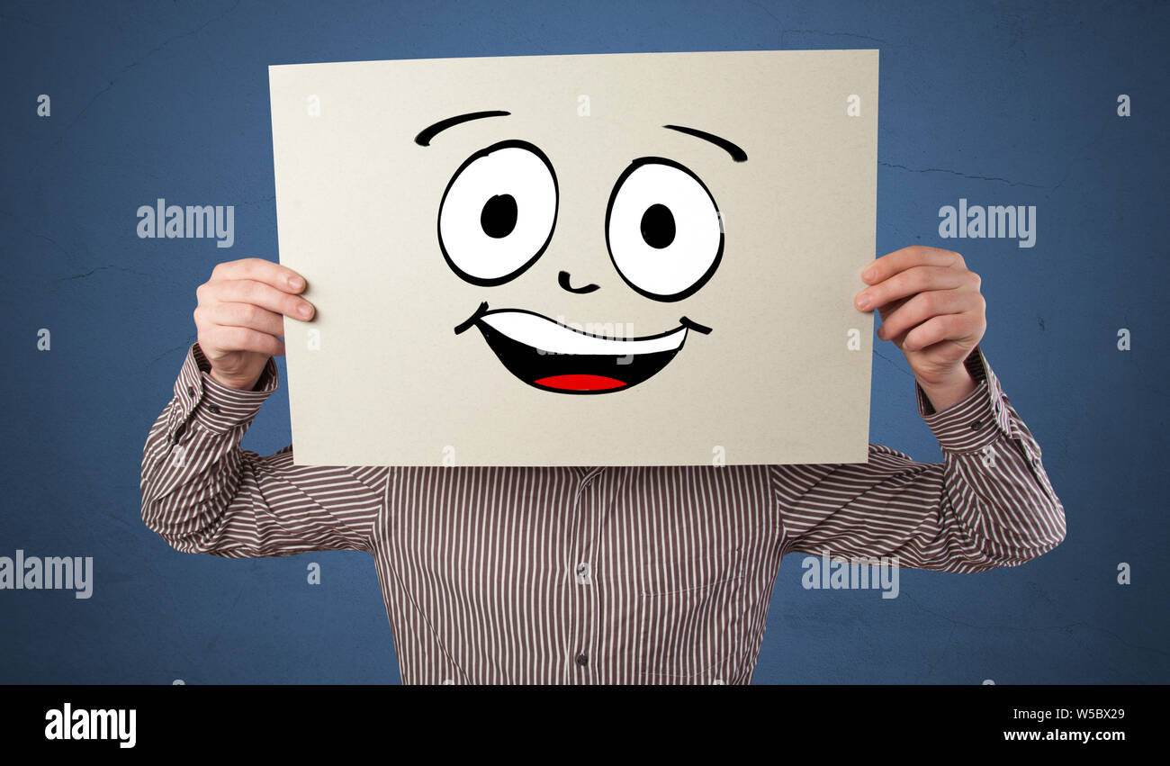 Young student holding a paper with laughing emoticon in front of his ...