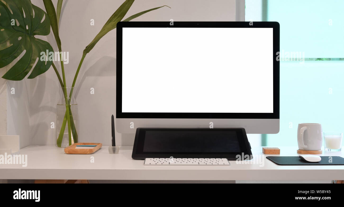 Relaxing work place with blank screen computer and office supplies on white wooden table in ...