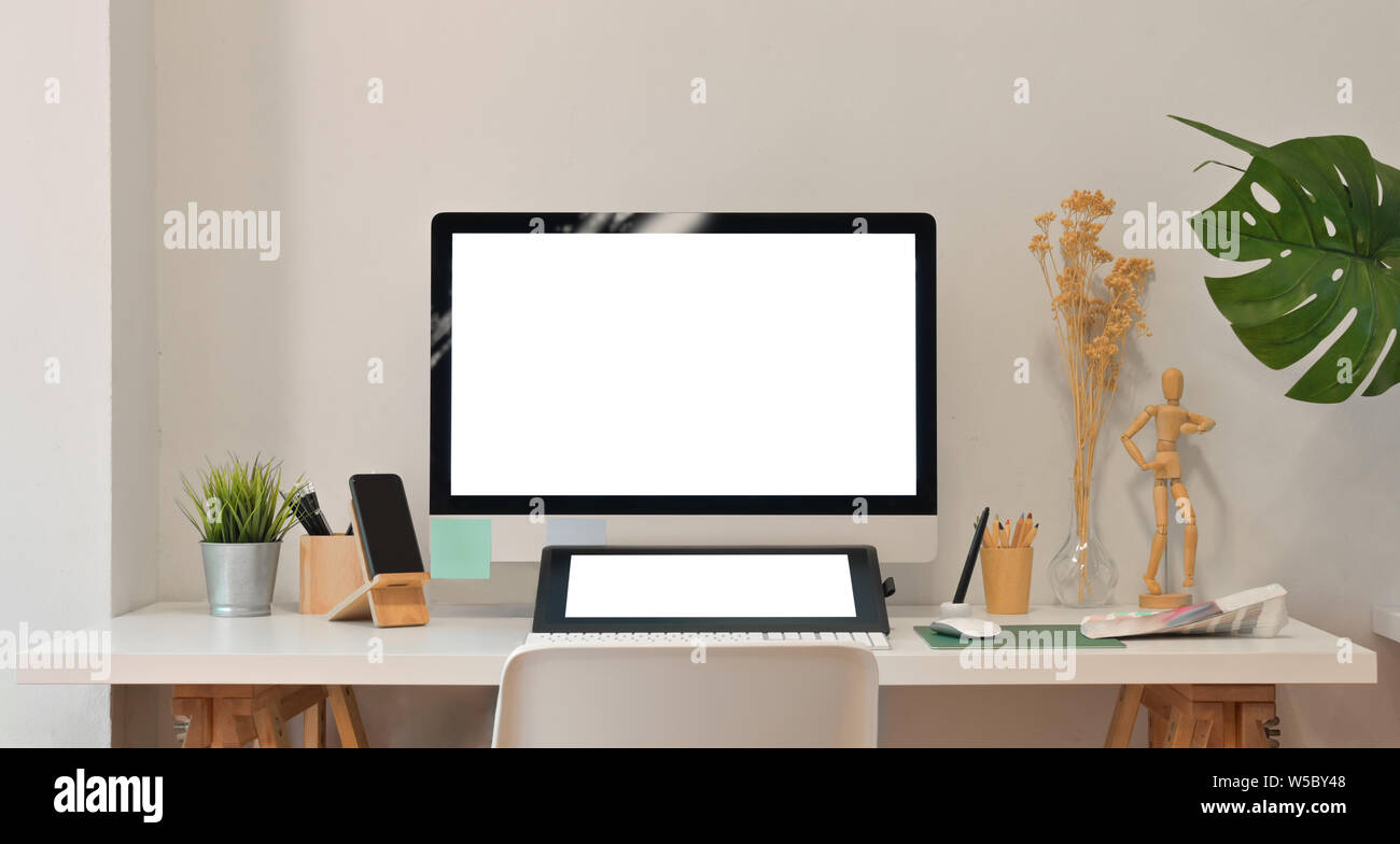 Blank screen computer and tablet in modern office room with copy space ...