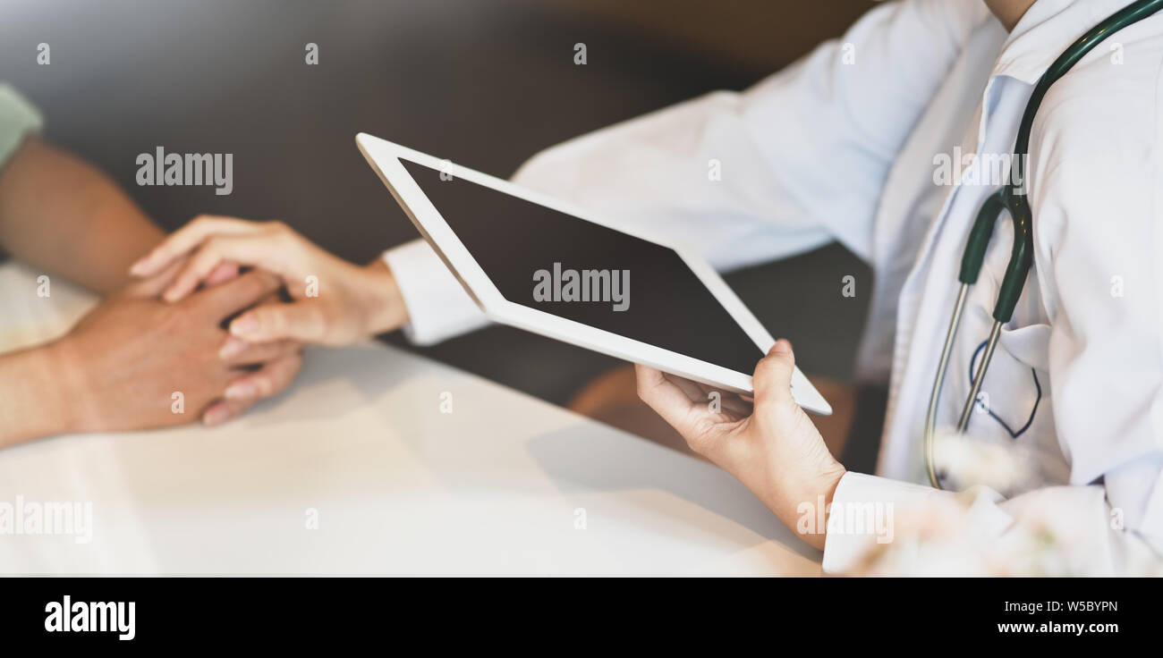 Doctor giving sympathy to patient while using tablet at the hospital ...