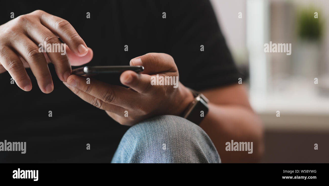 Young male touching his smartphone in his workplace with close up view ...