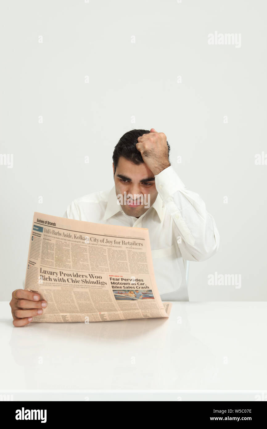 Businessman looking frustrated while reading a newspaper Stock Photo ...