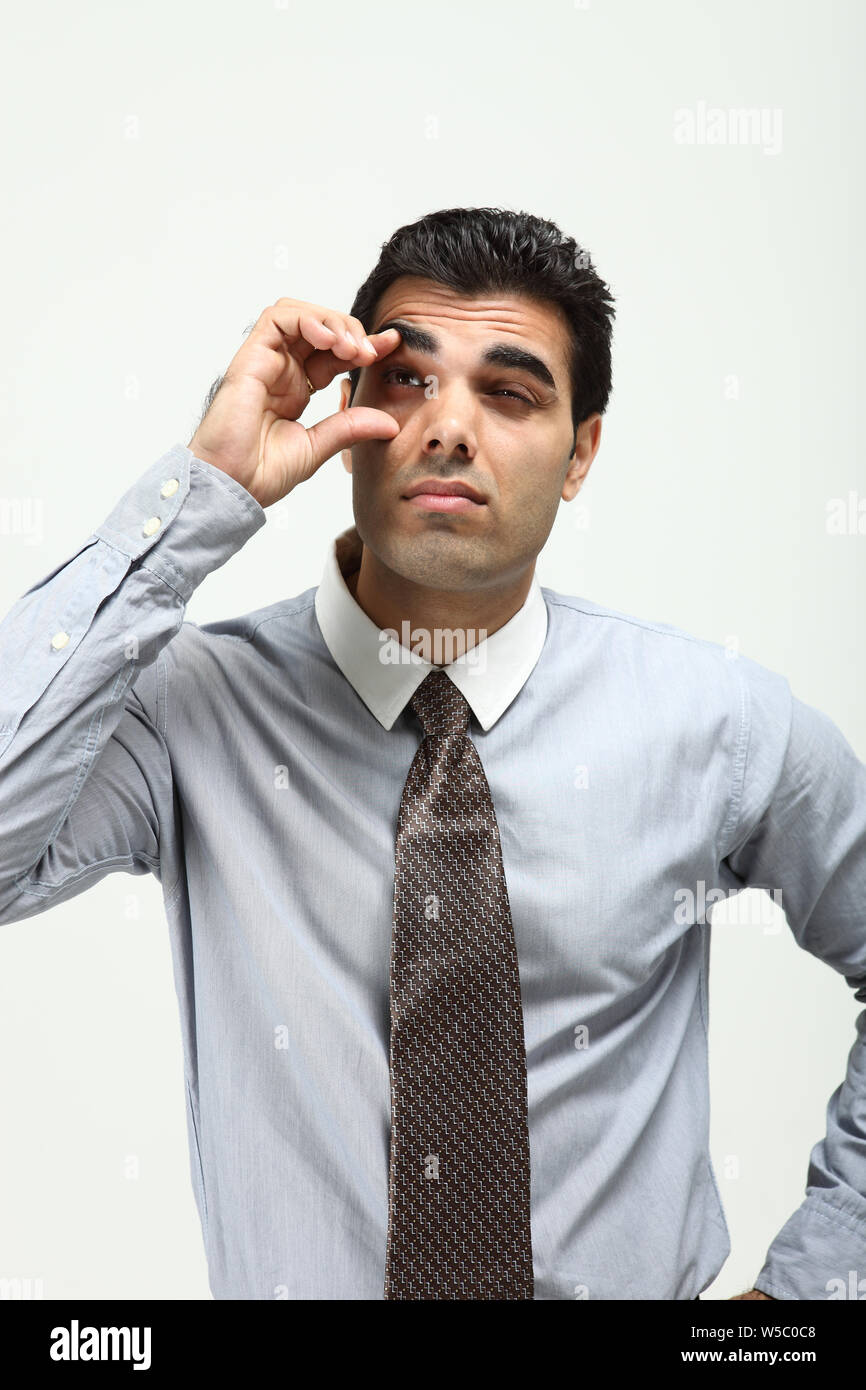 Businessman holding his eye open with his finger Stock Photo - Alamy