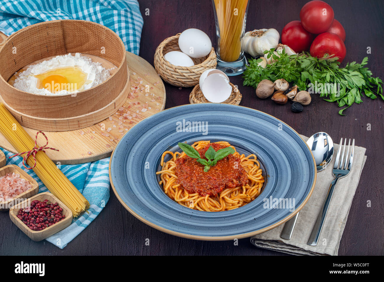 Spaghetti bolognese in a blue plate on a dark wood background.Top view ...