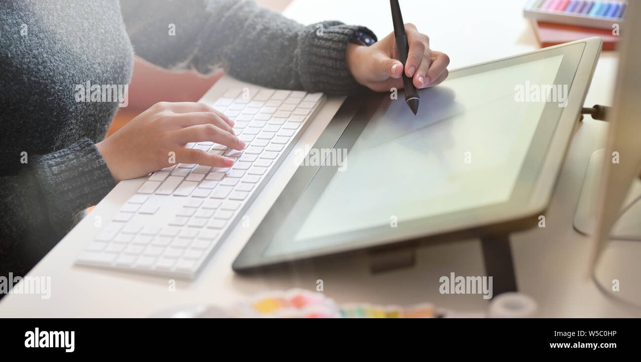 Graphic designer using digital drawing tablet and computer in studio ...