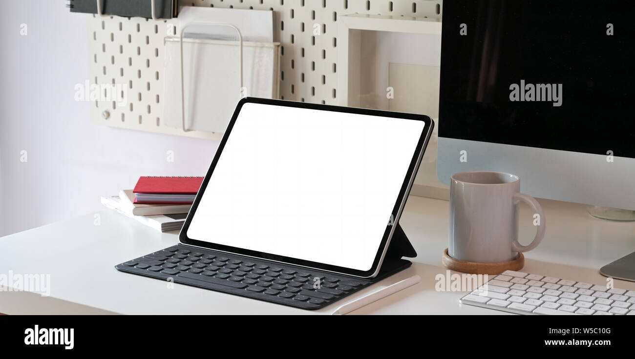 Blank white screen tablet with office supplies on white desk workspace ...