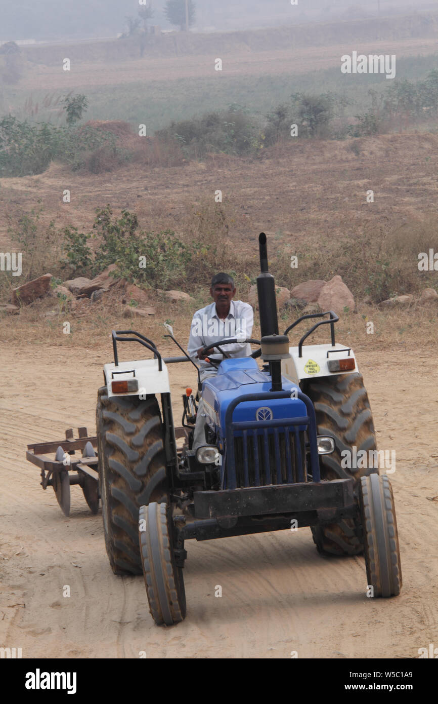 Farmer driving a tractor on a road Stock Photo - Alamy