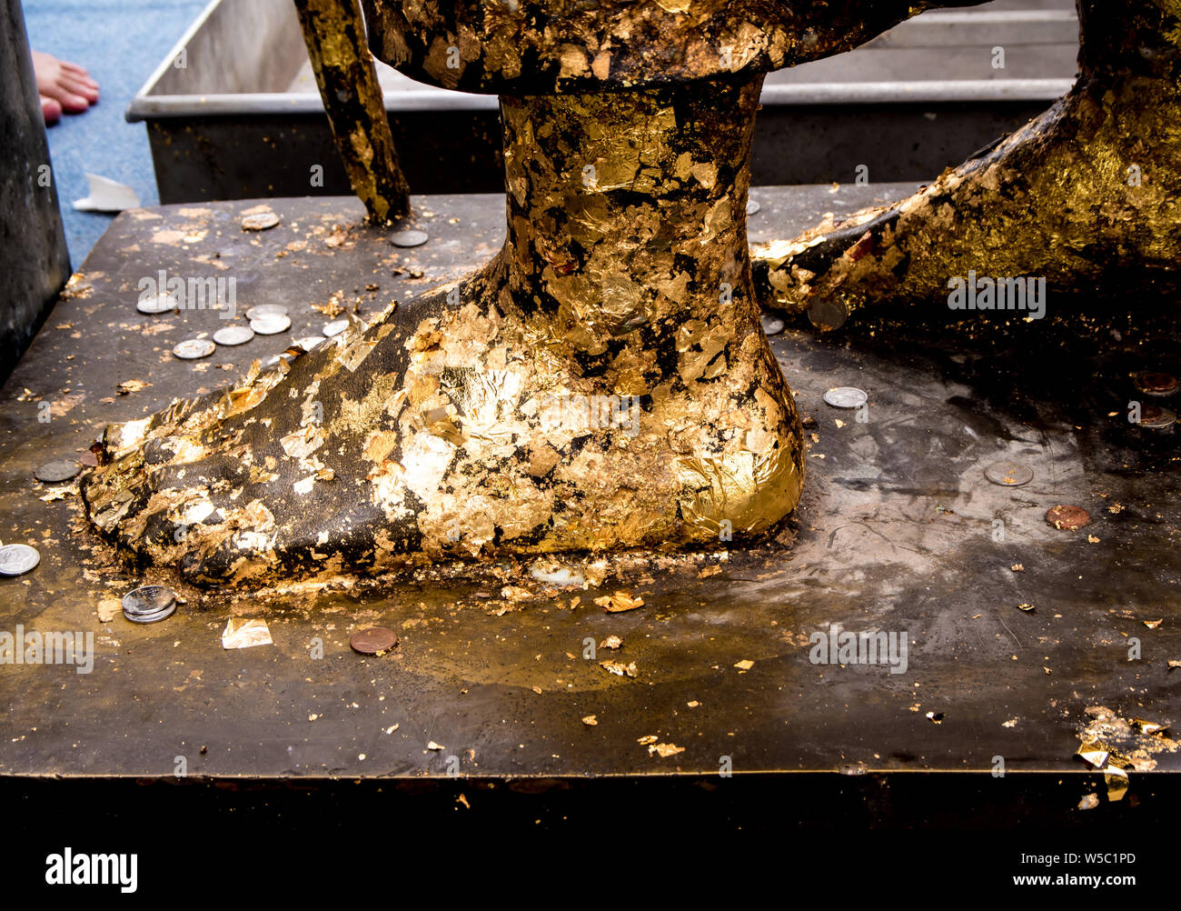 Golden leaf taped and Thai bath coin on the Buddha foot statue Stock ...