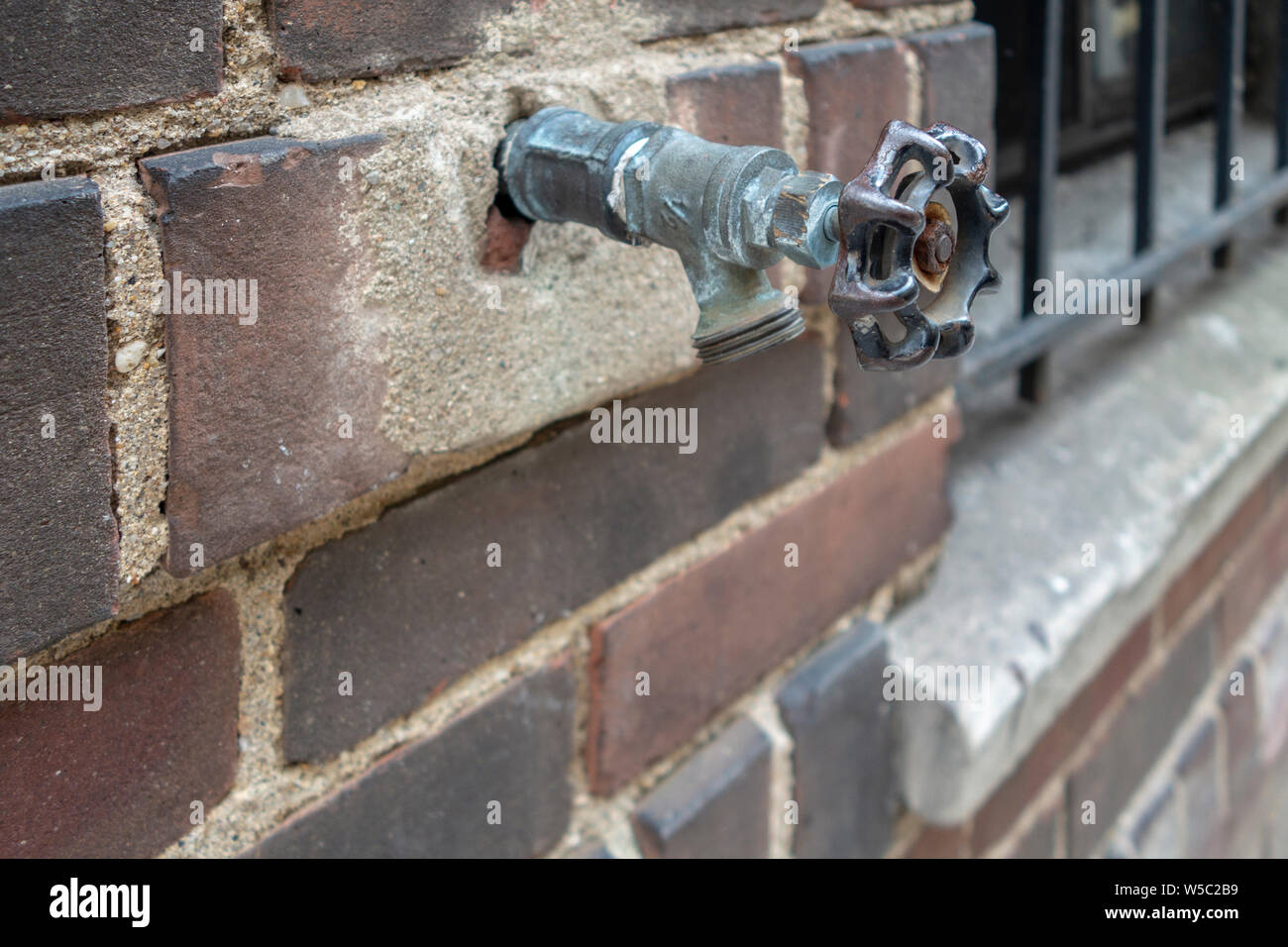 water spout sticking out of a brick wall ground level of a large city ...