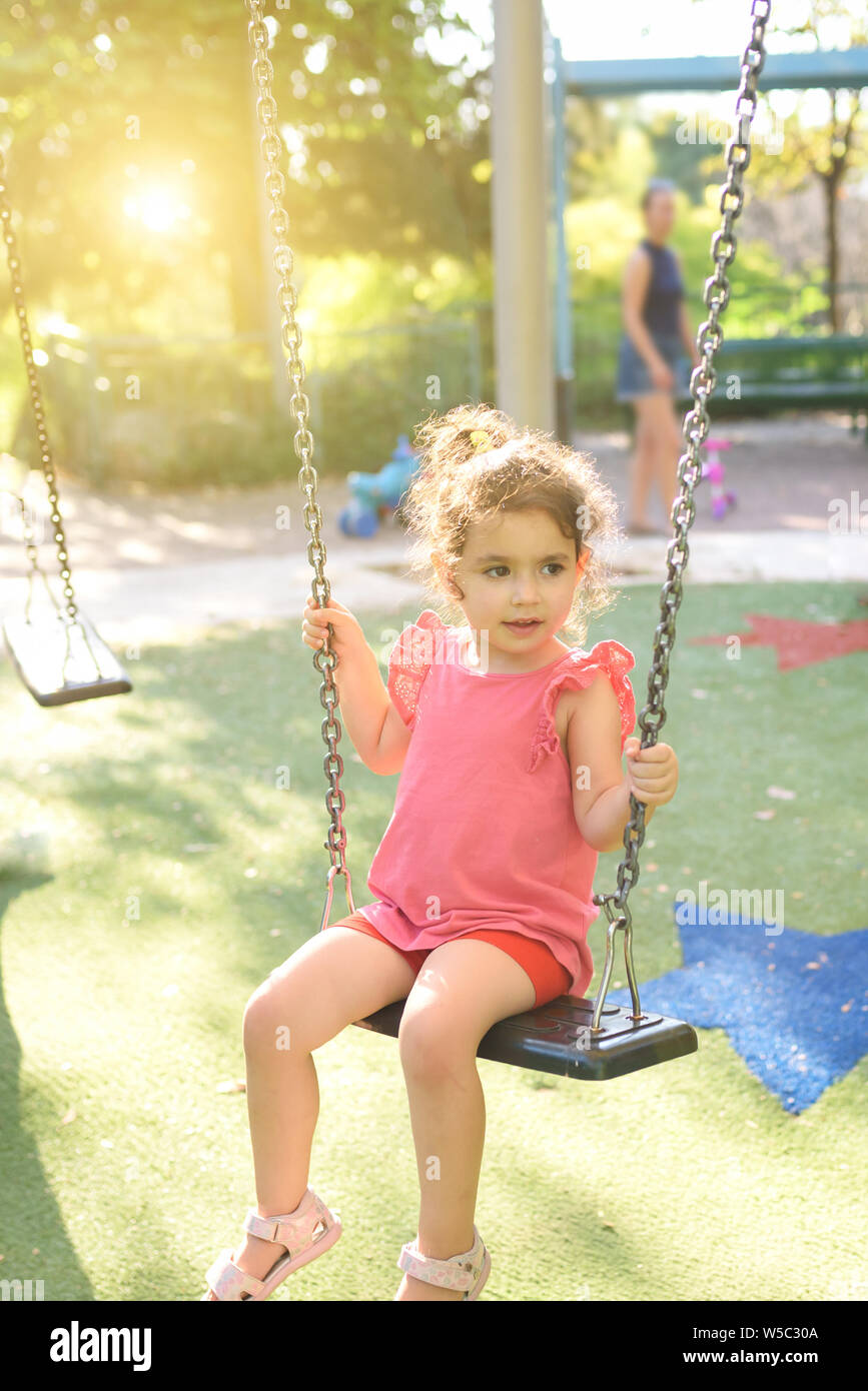Happy child girl laughing and swinging on a swing at the playground in summer Stock Photo - Alamy