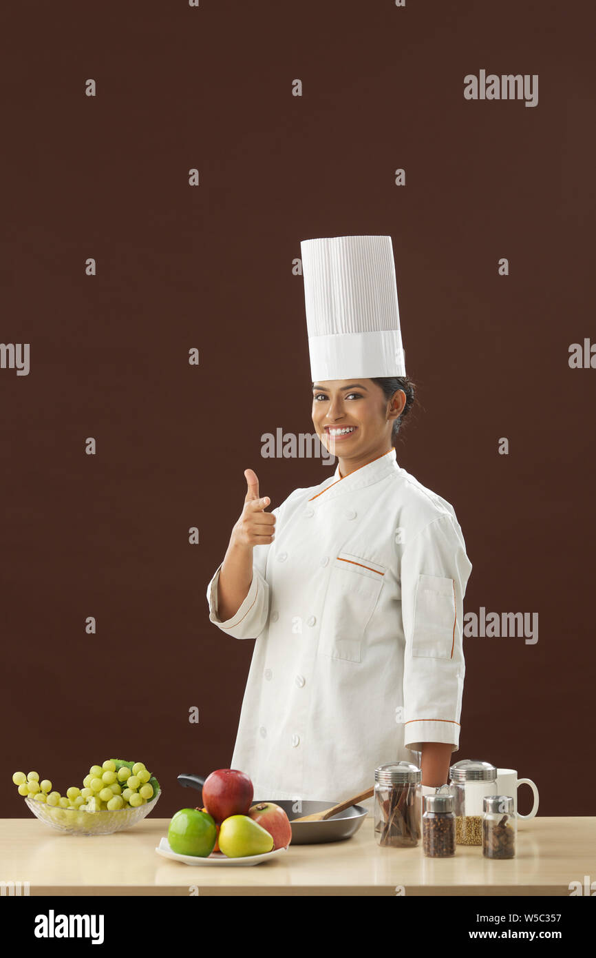 Chef gesturing at kitchen counter and smiling Stock Photo - Alamy