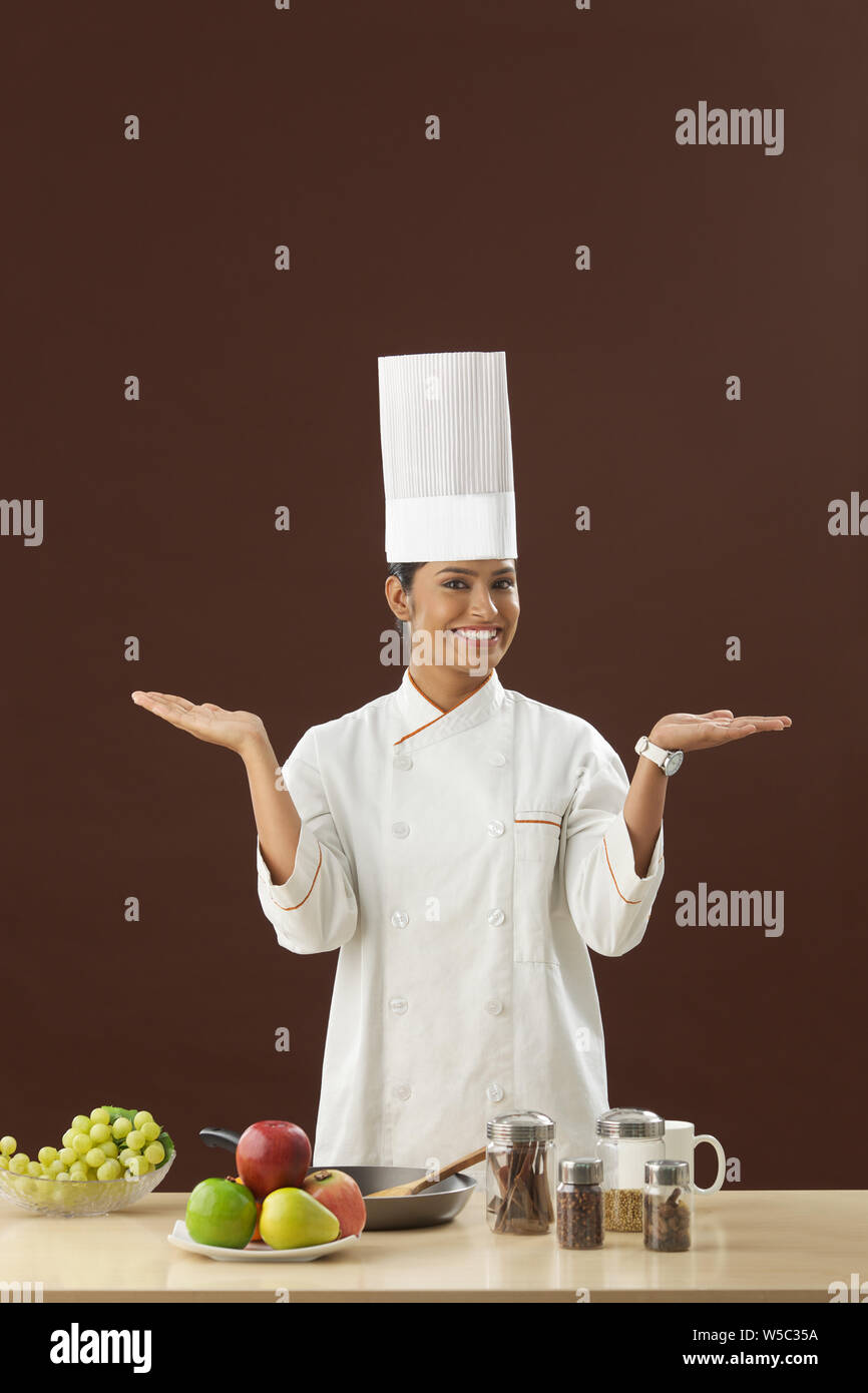 Chef gesturing at kitchen counter and smiling Stock Photo - Alamy
