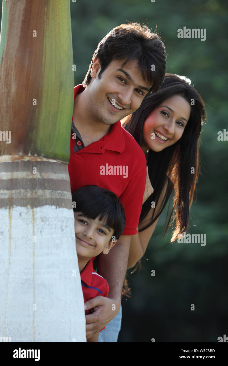 Family peeking out from behind tree Stock Photo - Alamy