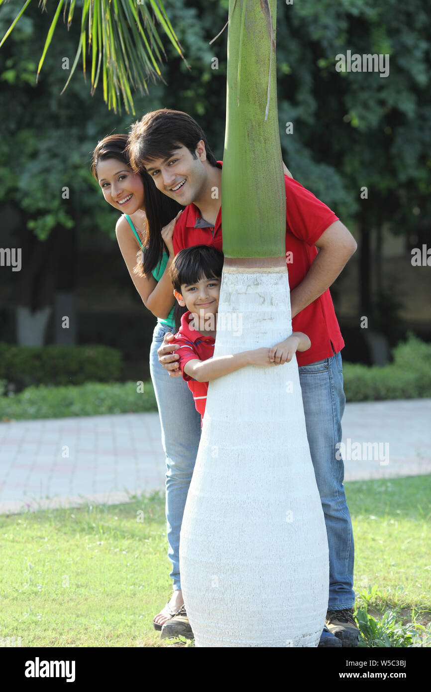 Family hiding behind a tree Stock Photo - Alamy