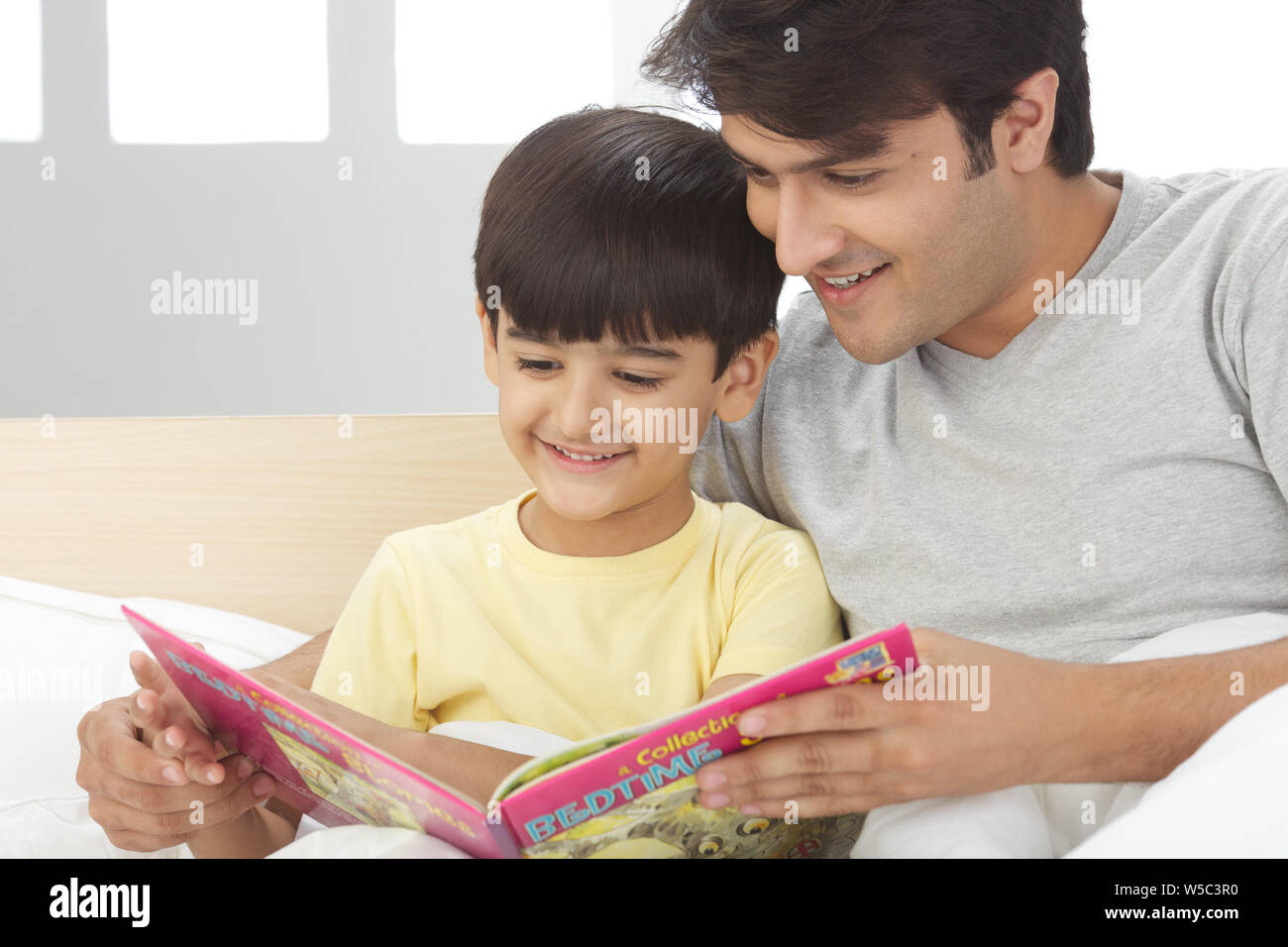 Boy reading storybook with his father on bed Stock Photo - Alamy