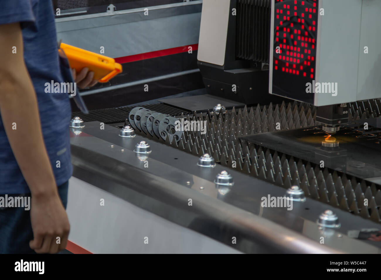 Industry worker operating laser cutting machine cutting metal sheet ...