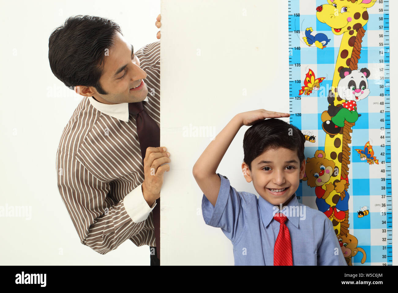 Man looking his son measuring his height Stock Photo - Alamy