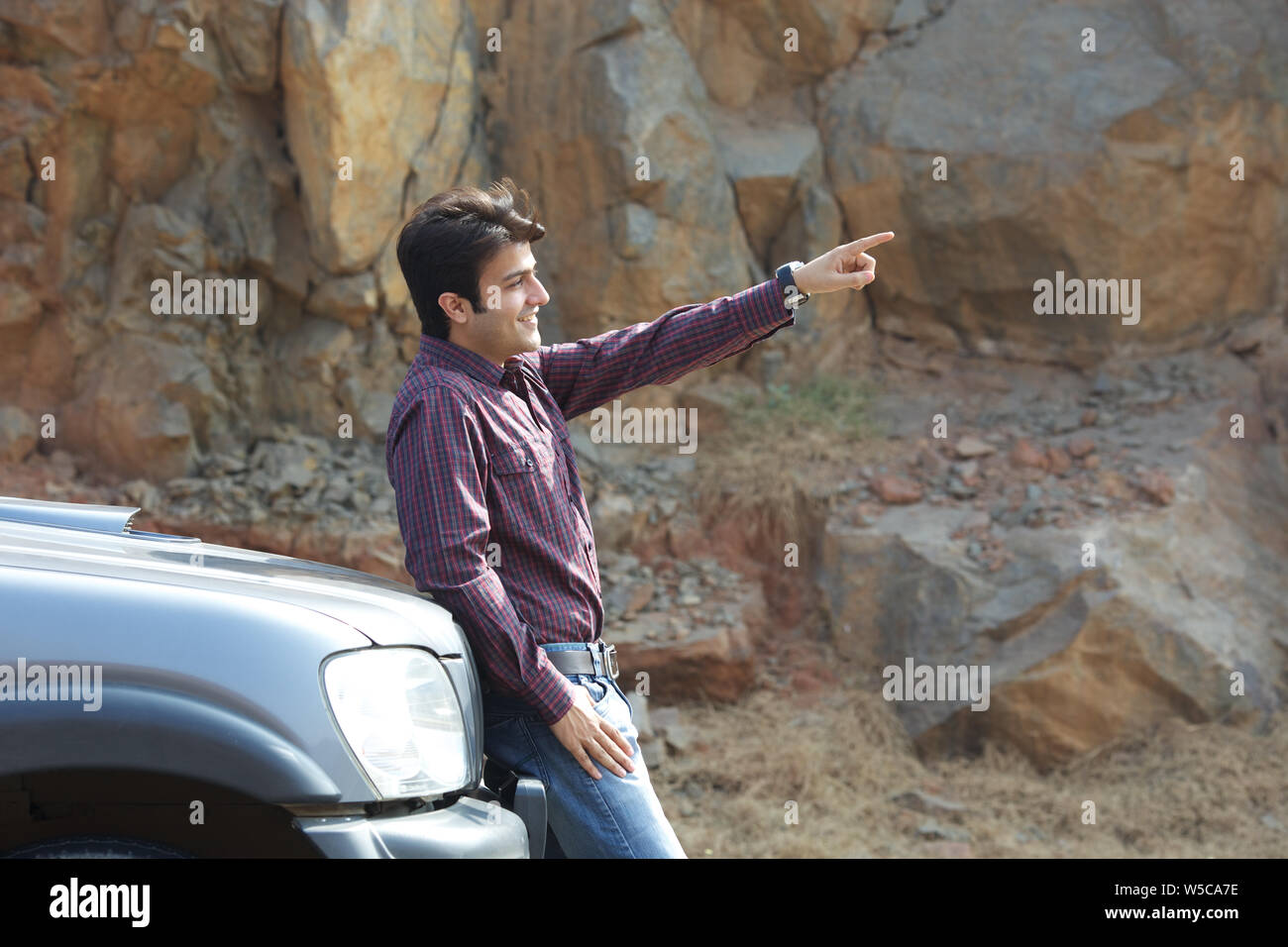 Man leaning against a car and pointing Stock Photo - Alamy
