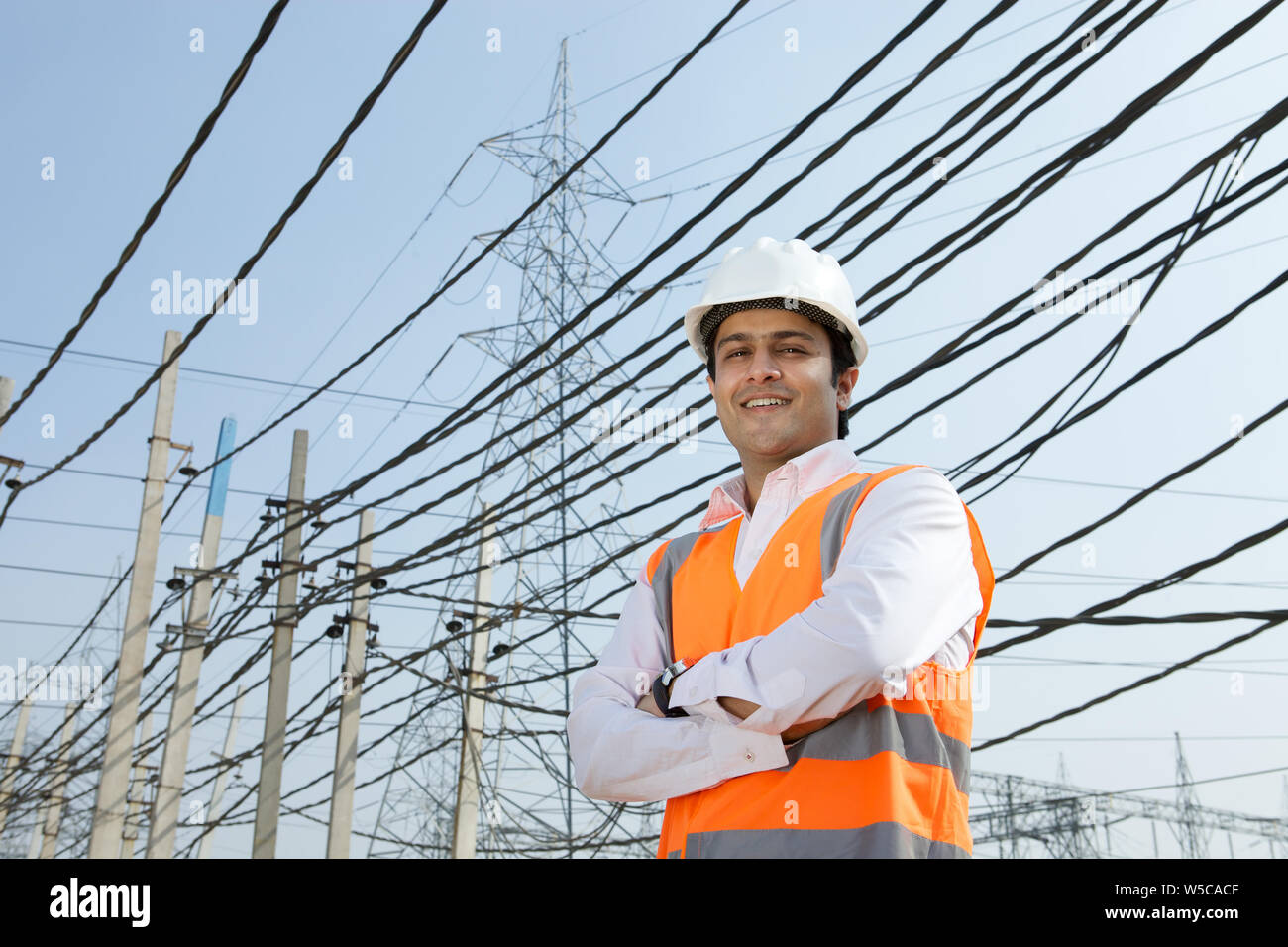 Engineer standing with arms crossed and smiling Stock Photo - Alamy