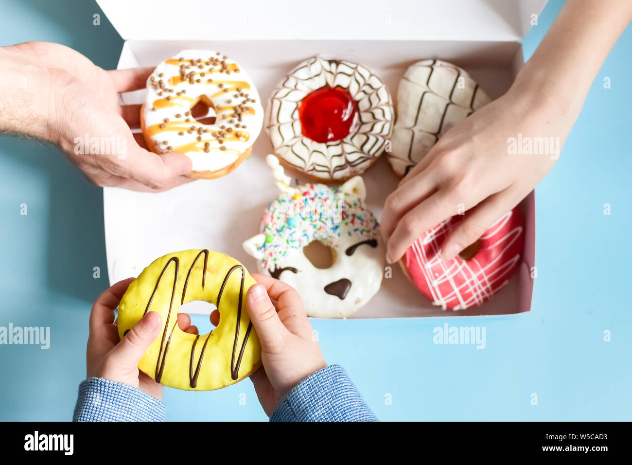 People hands takes donuts from donuts box over blue background. Family ...
