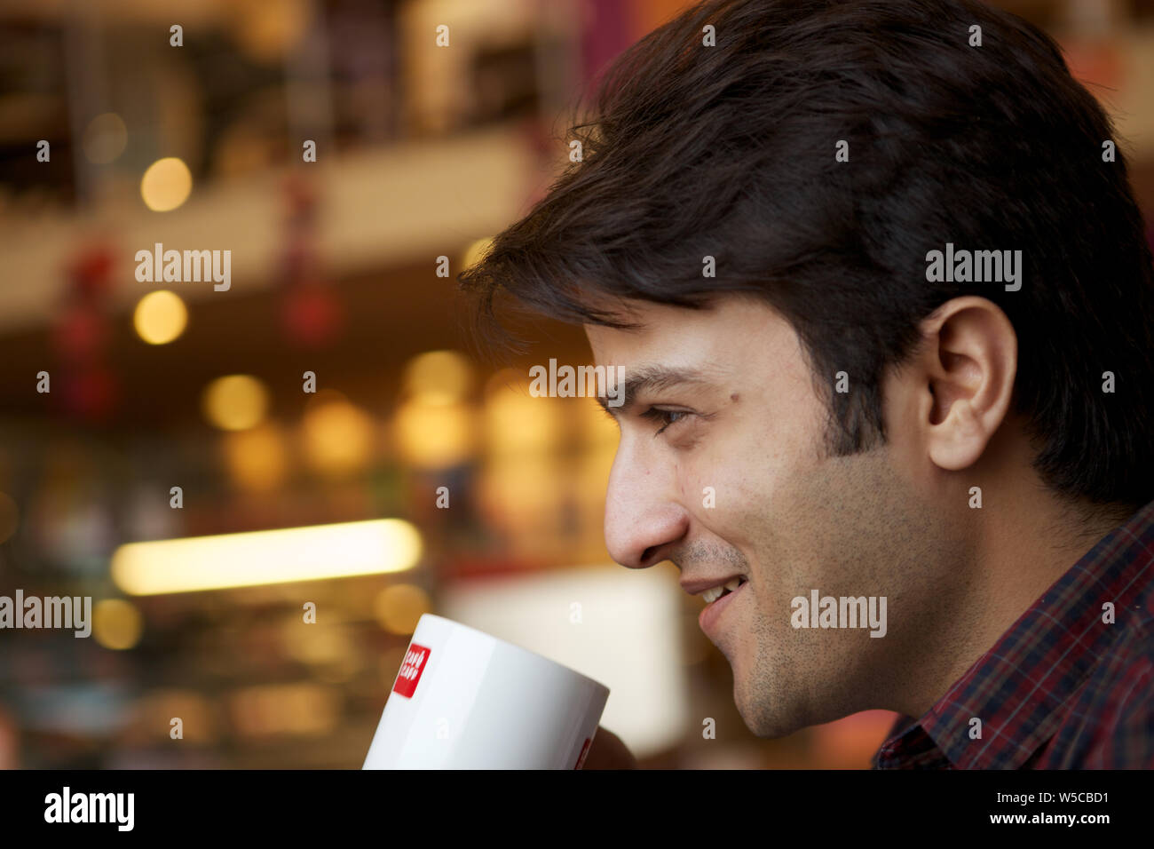 Indian young man having a cup of coffee in a cafeteria Stock Photo - Alamy
