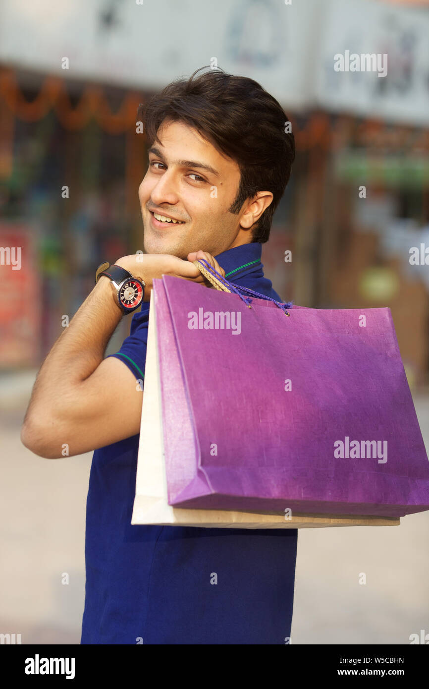 Man carrying shopping bags and smiling Stock Photo - Alamy