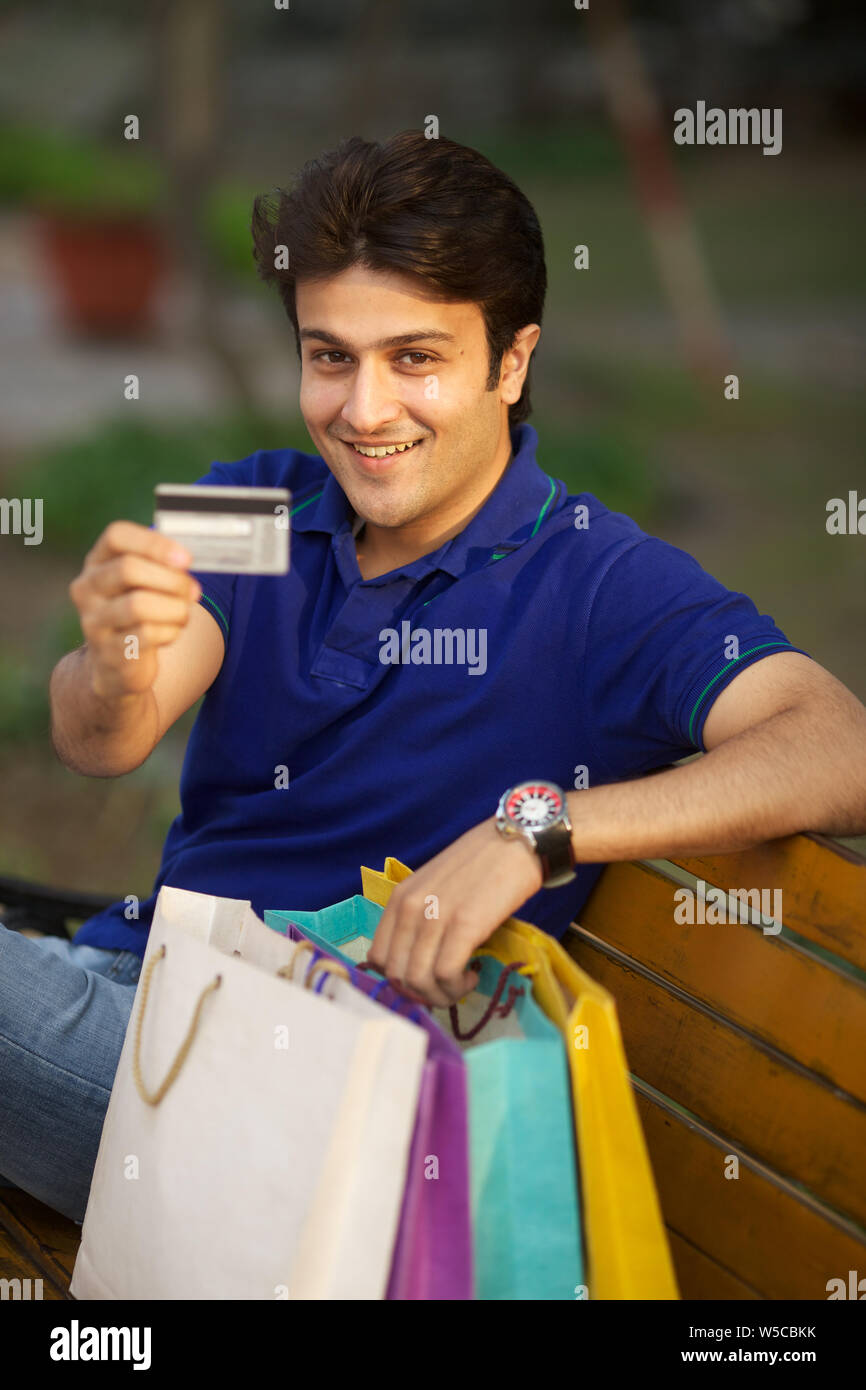 Man sitting on a park bench and showing credit card Stock Photo - Alamy