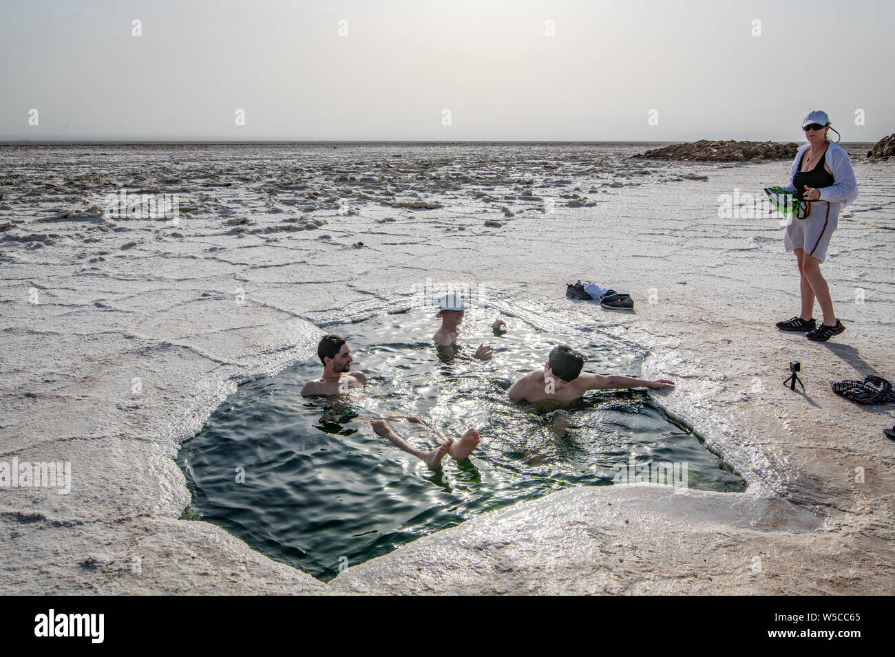 Tourists relax inside the water of Lake Karum, visible through a hole ...
