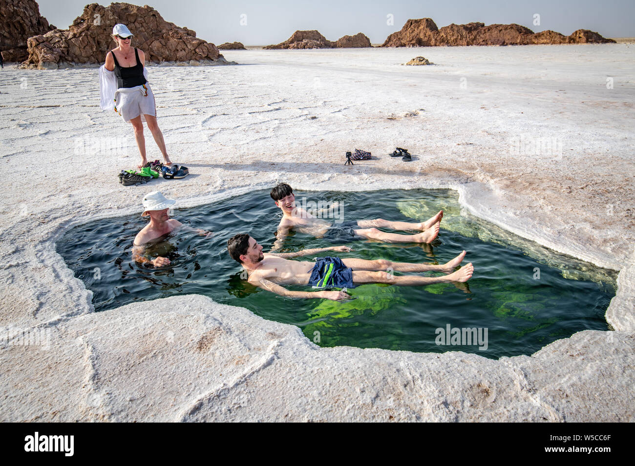 Tourists relax inside the water of Lake Karum, visible through a hole ...