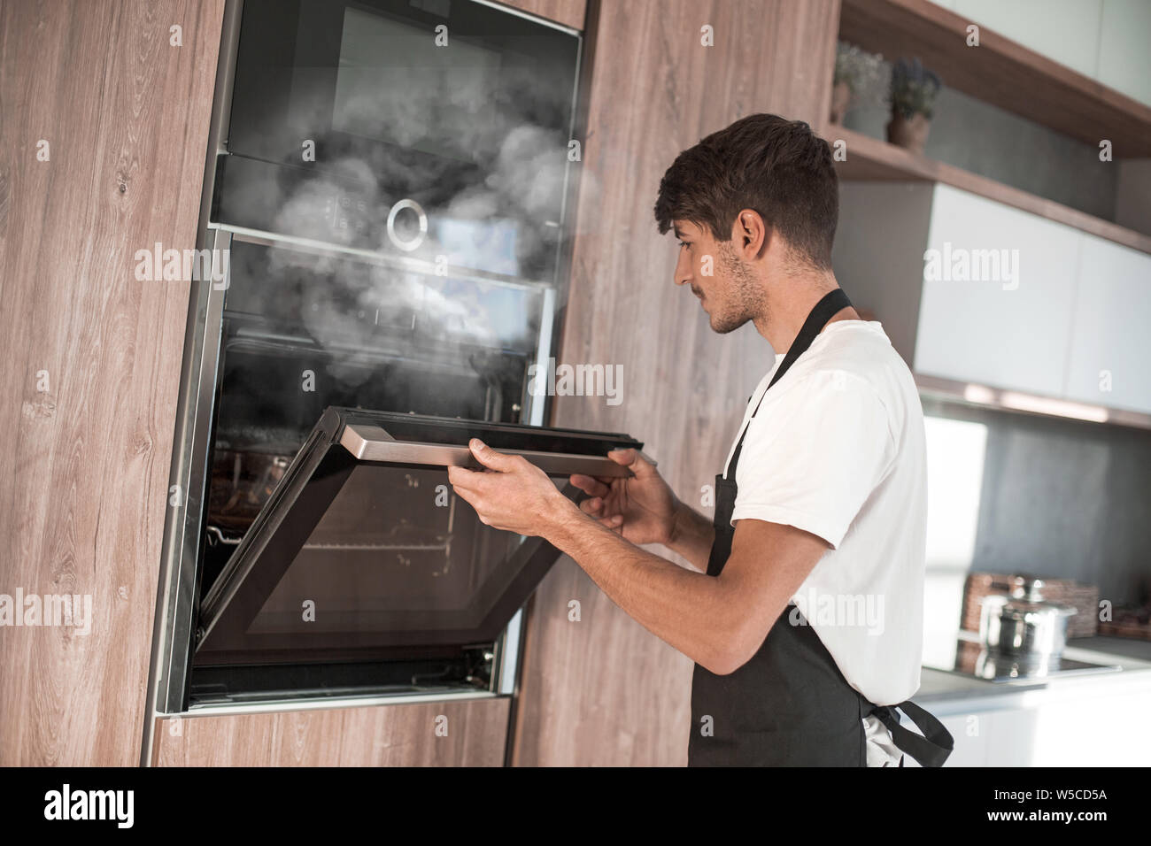 man opening the oven in the home kitchen Stock Photo - Alamy