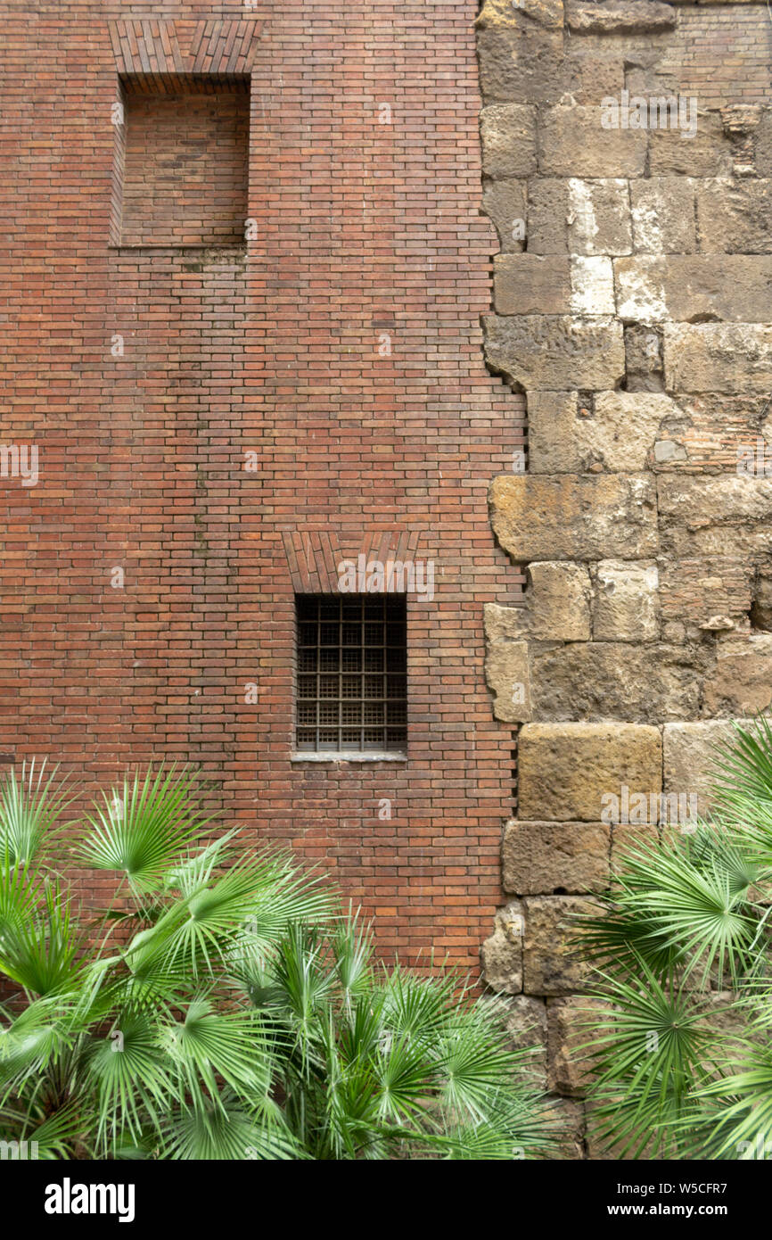 Detail of a red brick and older stone wall butting up to each other ...