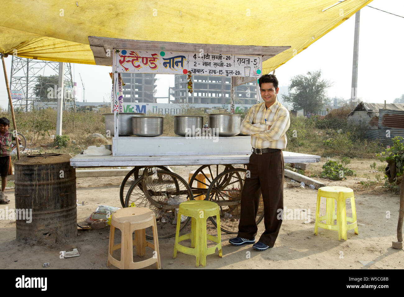 Seller standing with his arms crossed at a food stall Stock Photo - Alamy