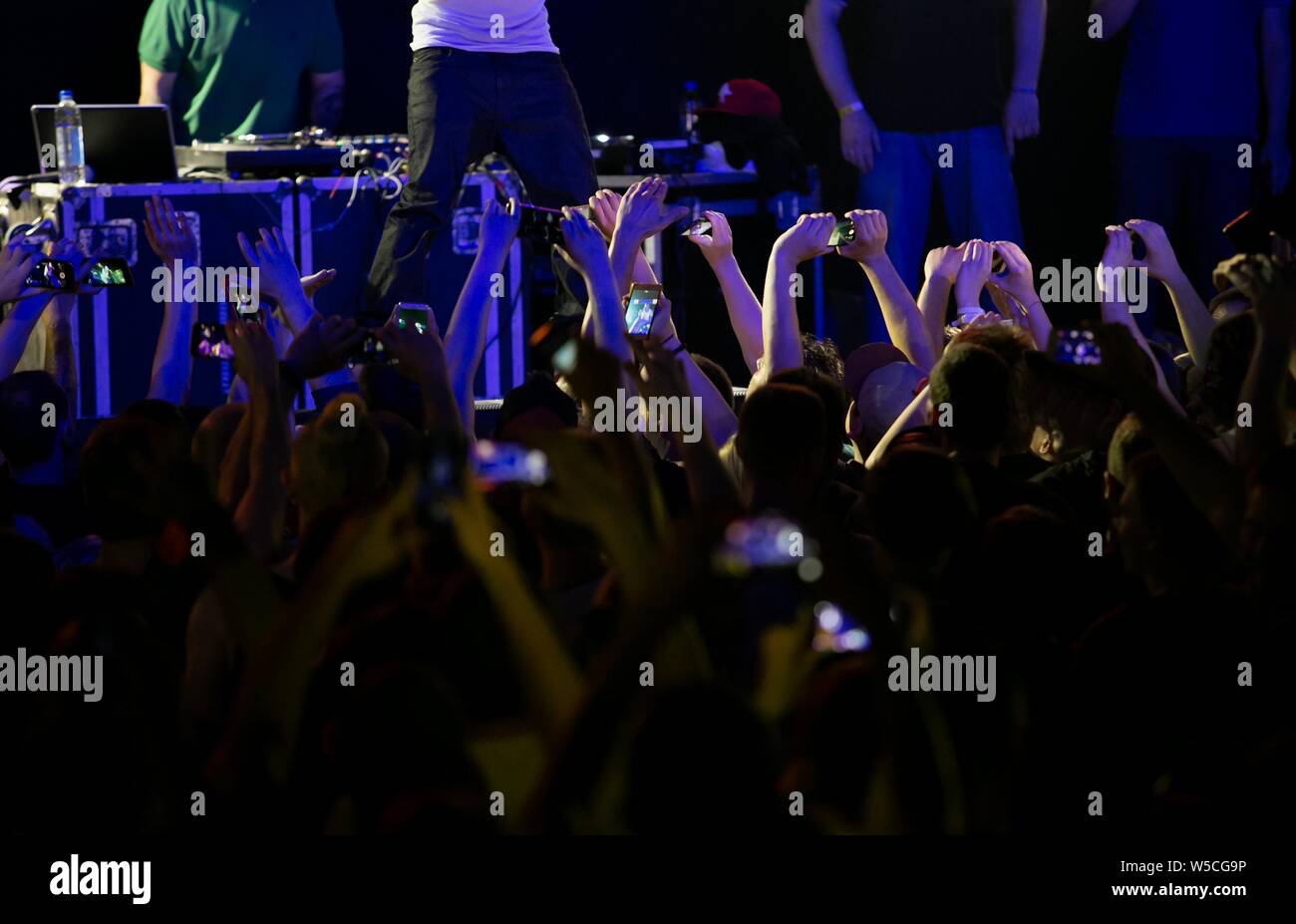 Rap concert fans taking pictures of famous rapper on stage in nightclub ...