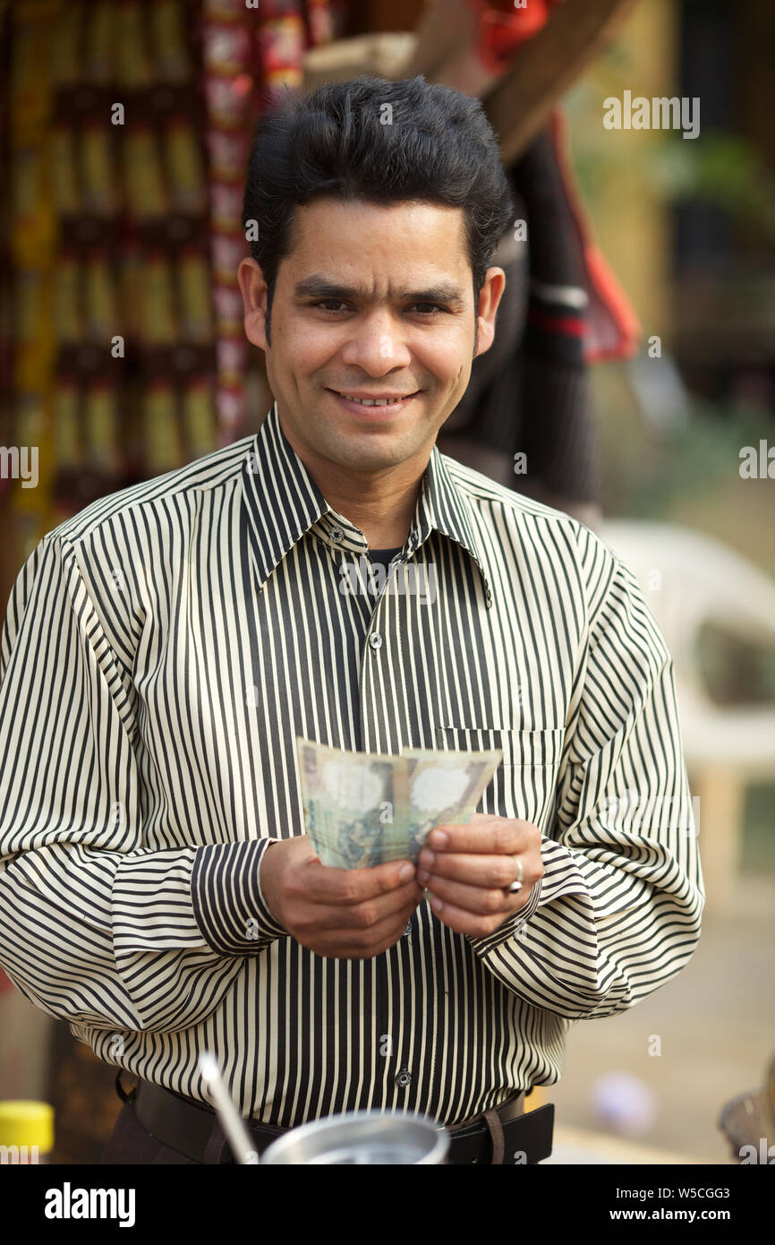 Indian man counting hundred rupees banknotes Stock Photo - Alamy