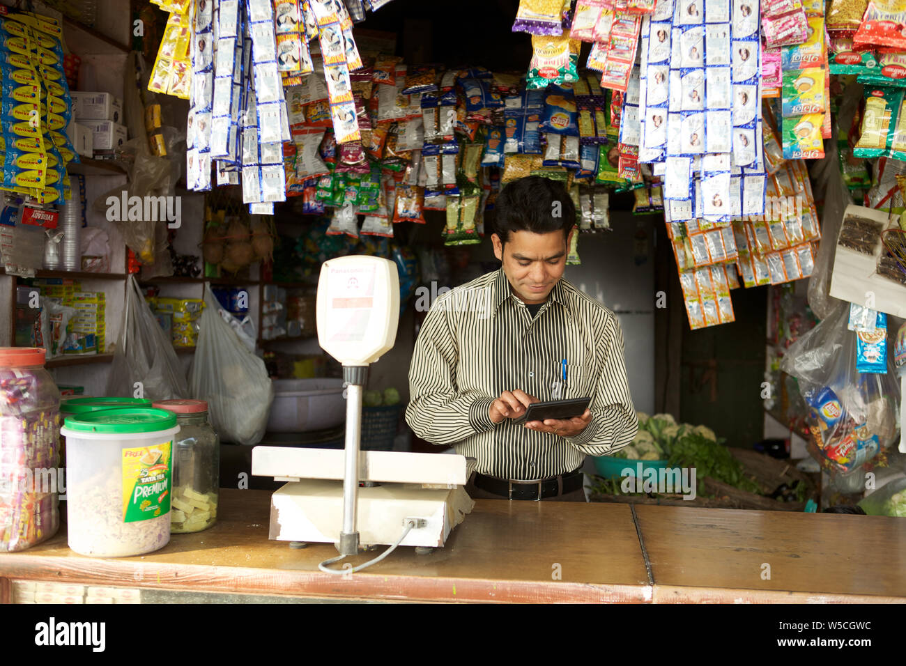 Shopkeeper using calculator in grocery shop Stock Photo - Alamy