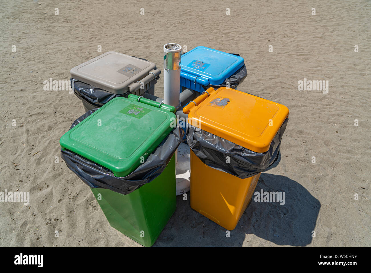 four different coloured garbage cans stand at the beach Stock Photo - Alamy