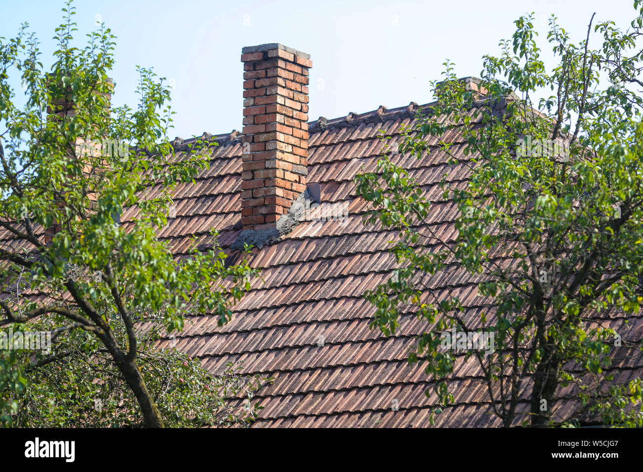 Details with the old ceramic roof tiles and with the red brick chimney ...