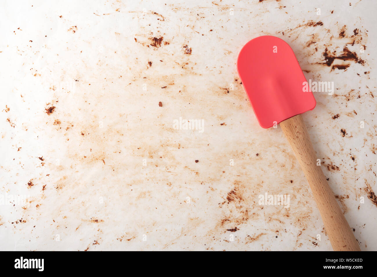 Spatula on baking paper with chocolate stain, top view, background with ...