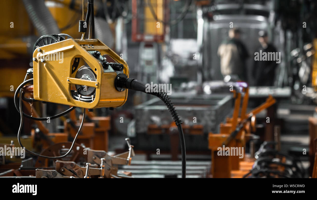 Welding machine on the background of people on the conveyor. Heavy ...